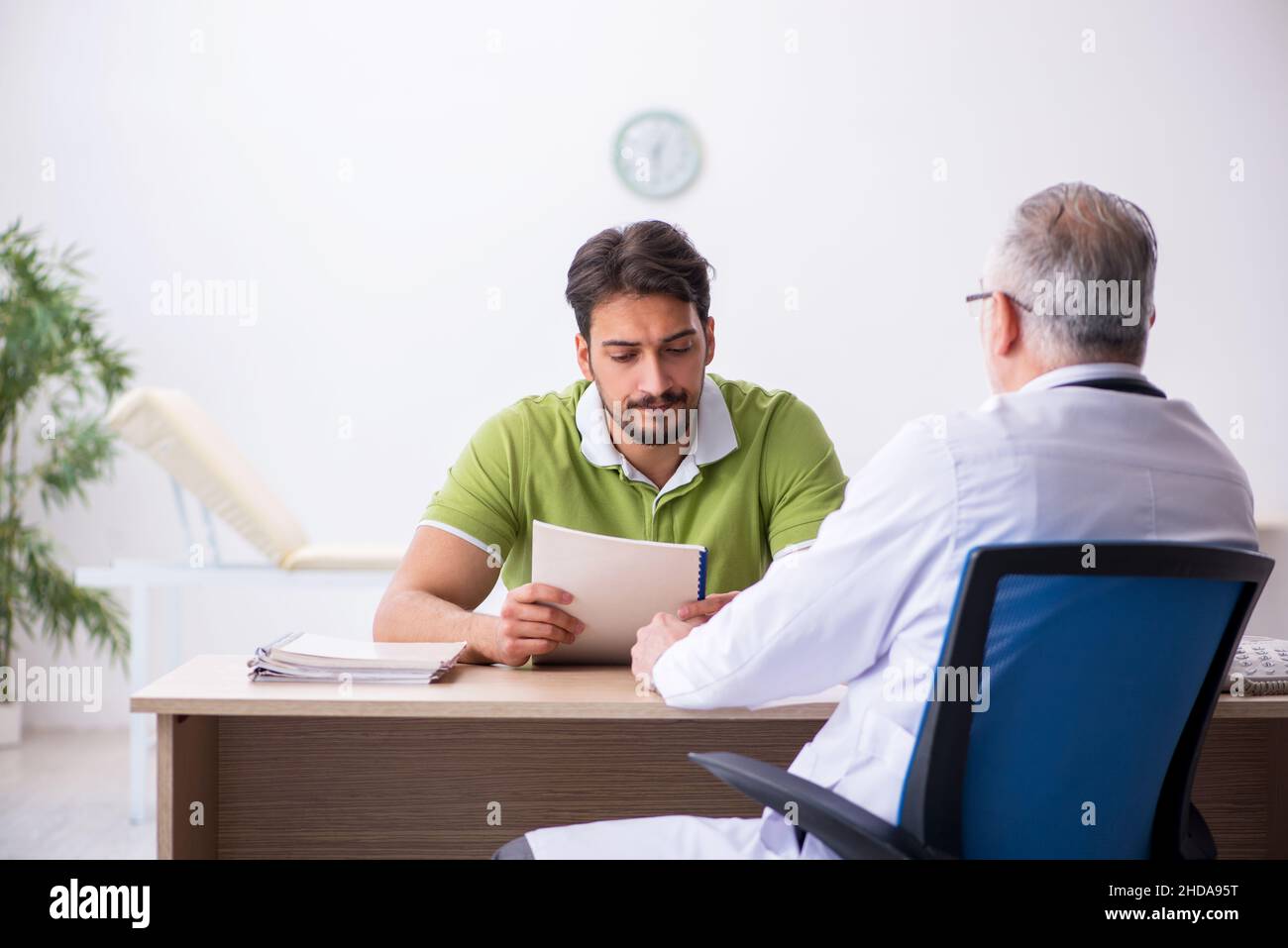 Young man visiting old doctor Stock Photo - Alamy