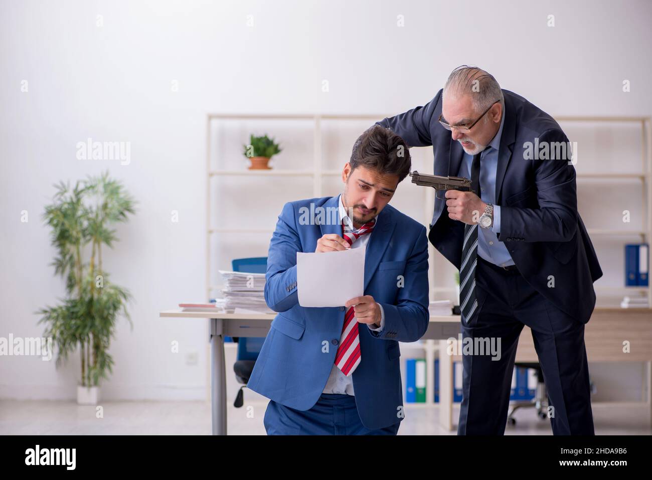 Old boss and young employee in bullying concept Stock Photo - Alamy