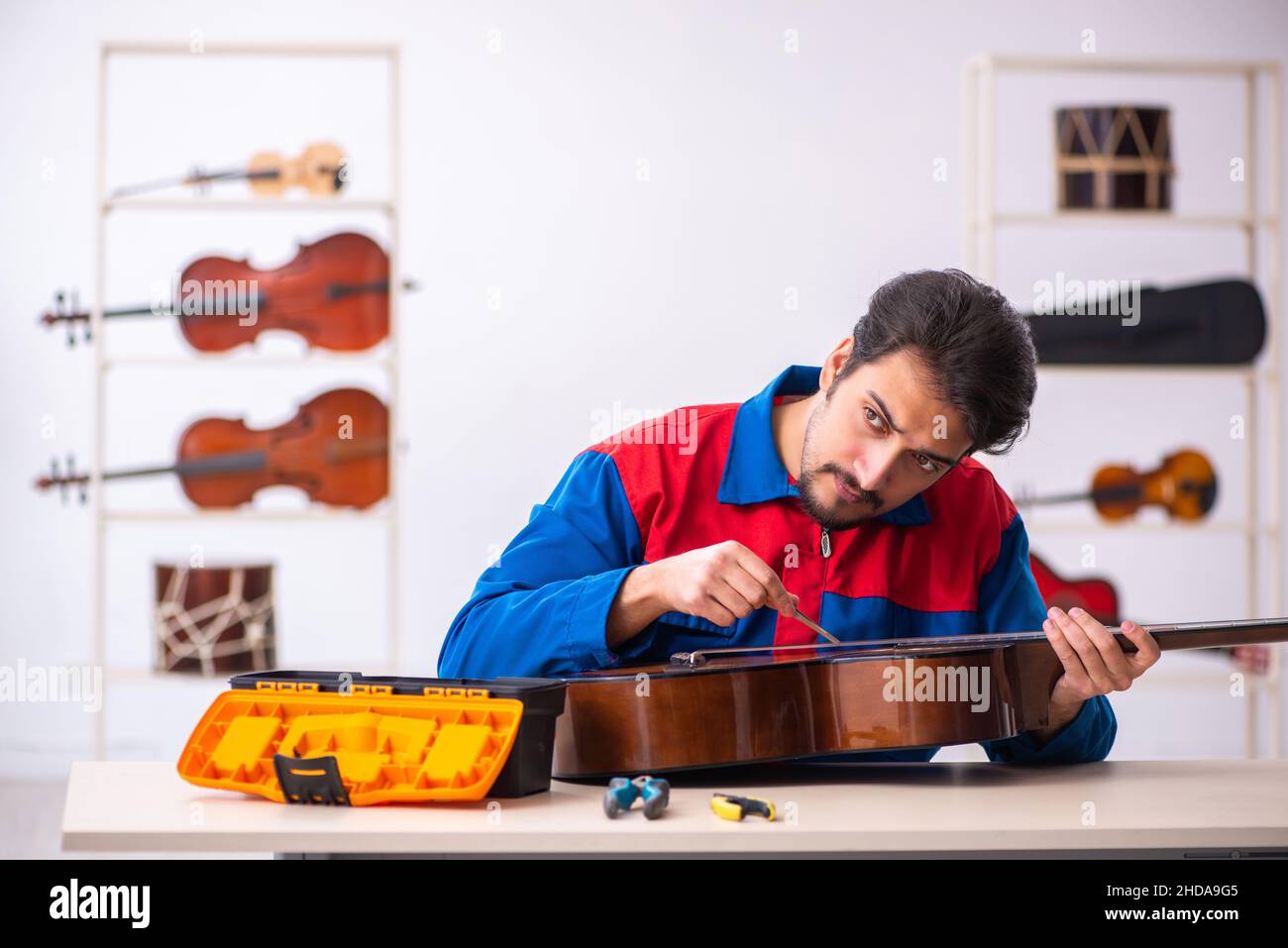 Young repairman repairing musical instruments at workplace Stock Photo ...