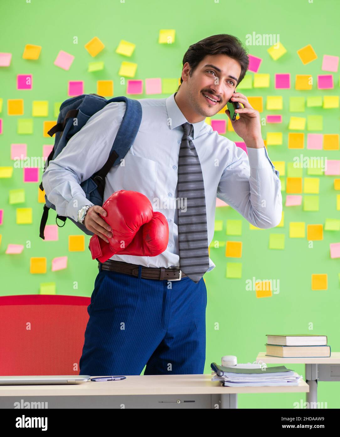 Man with boxing gloves in the office with many conflicting priorities ...