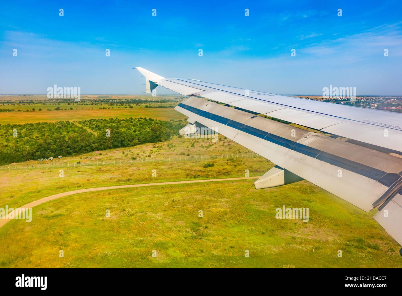 View of airplane wing, blue skies and green land during landing ...