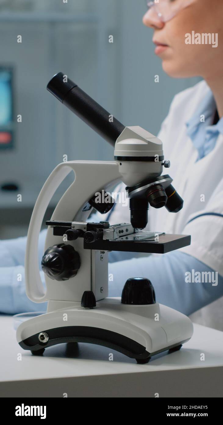 Close up of microscope tool while scientist analyzing petri dish and ...