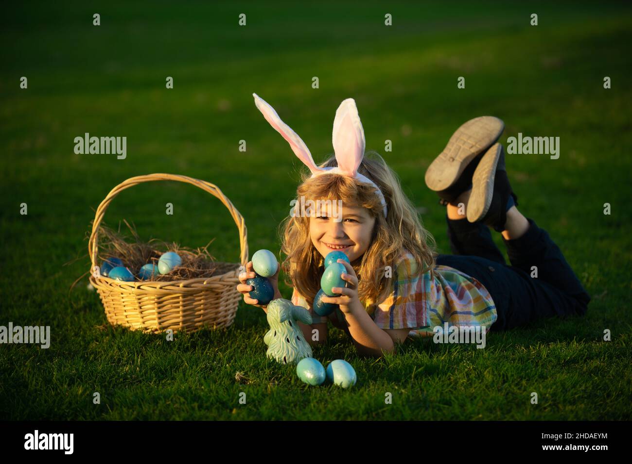 Children hunting easter eggs. Kid boy lying on the grass and finding ...