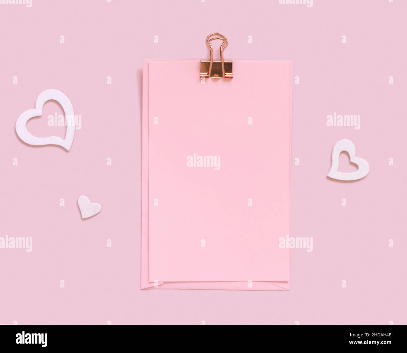 Pink paper card with clip near white hearts on pink top view. Minimal ...