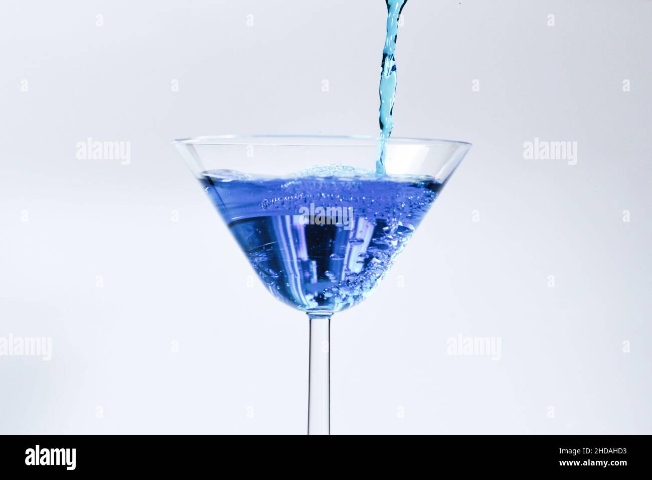 Cocktail with blue liquid in glass. Glass with blue water pouring with ...