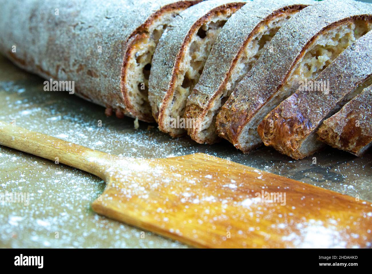 Fresh whole grain sliced bread sprinkled with flour lies on the table ...