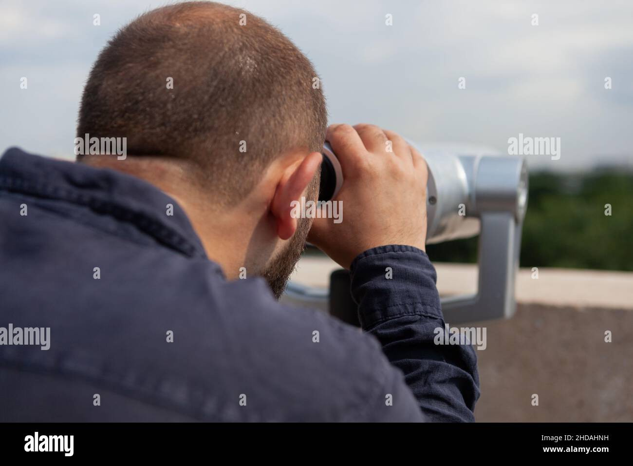 Caucasian male tourist watching through binoculars panoramic telescope ...