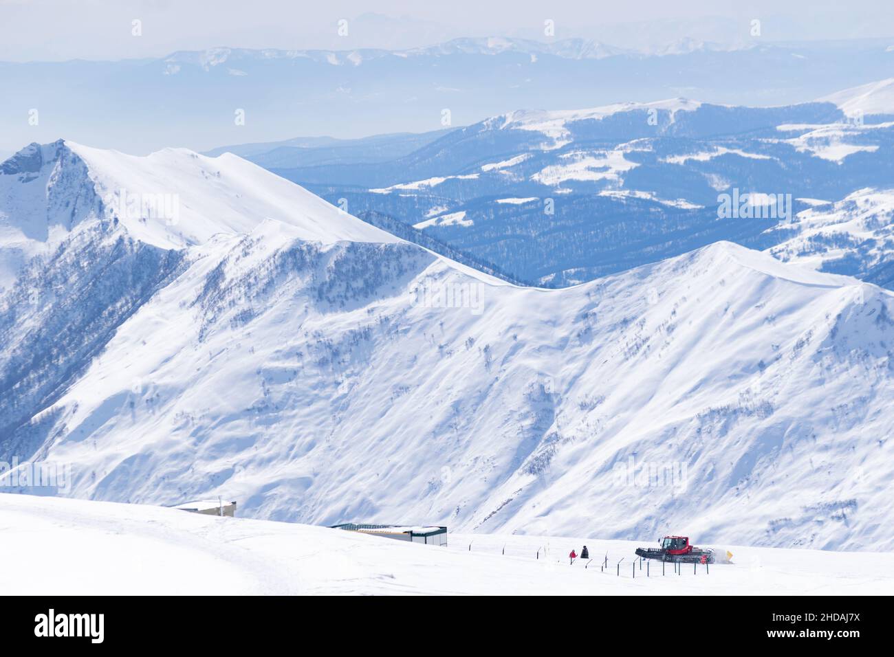 Red ratrac machine drives in Gidauri ski resort surounded by white high ...