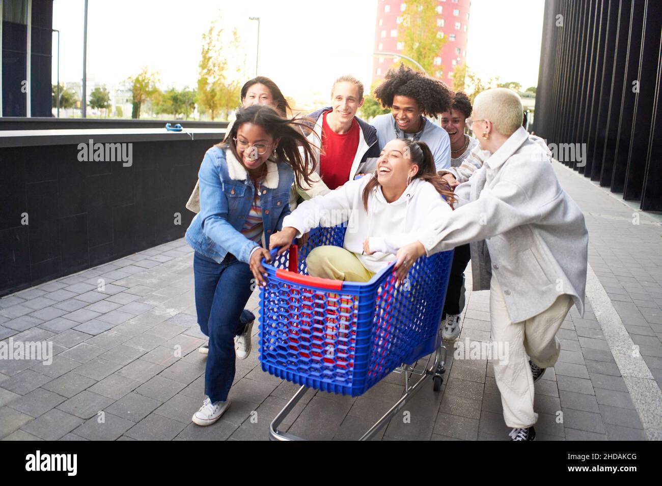 Crazy friends making a racing challenge with shopping cart. Multiracial ...
