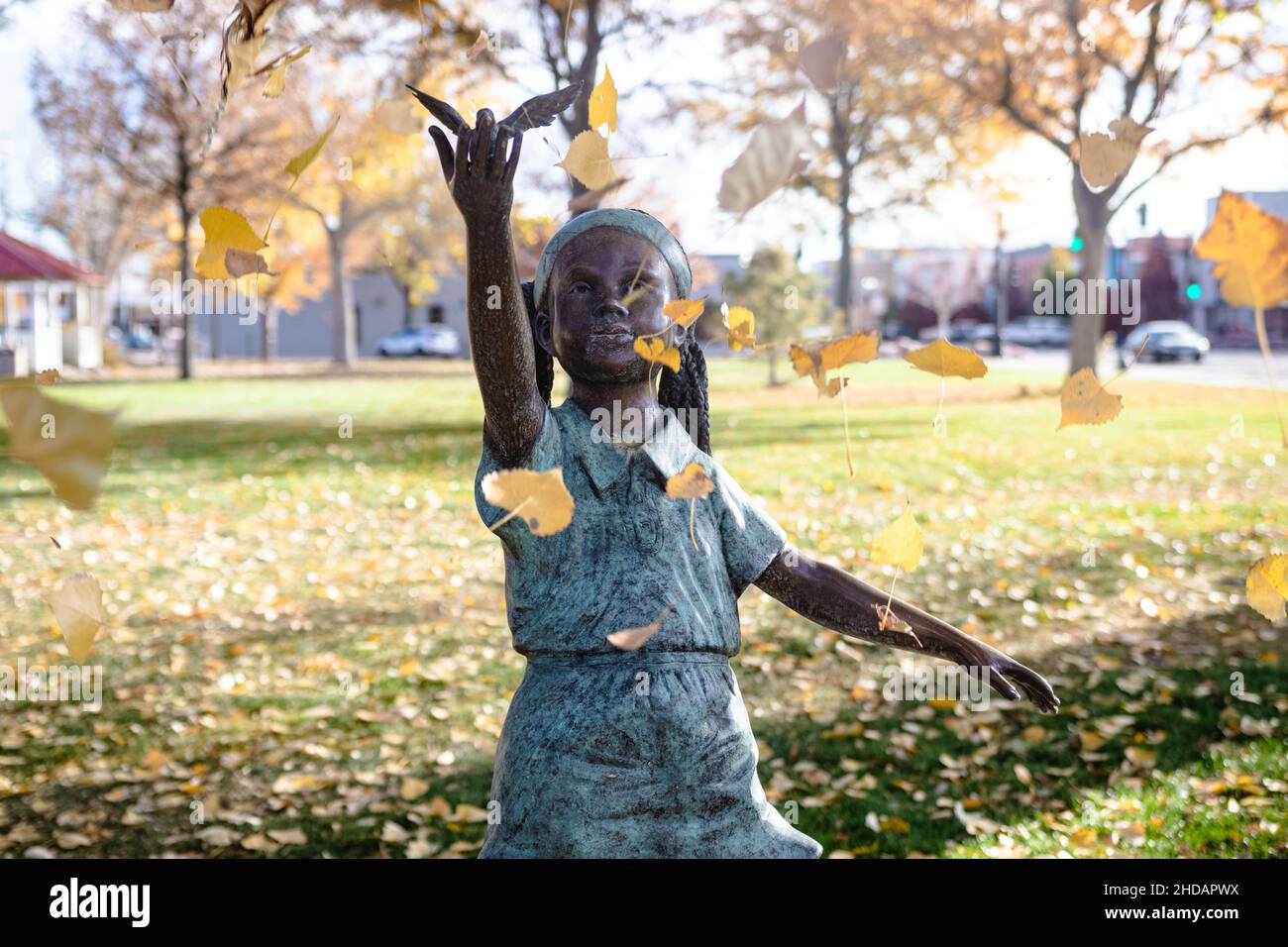 Bronze statue of a girl releasing a bird, while leaves falling around ...