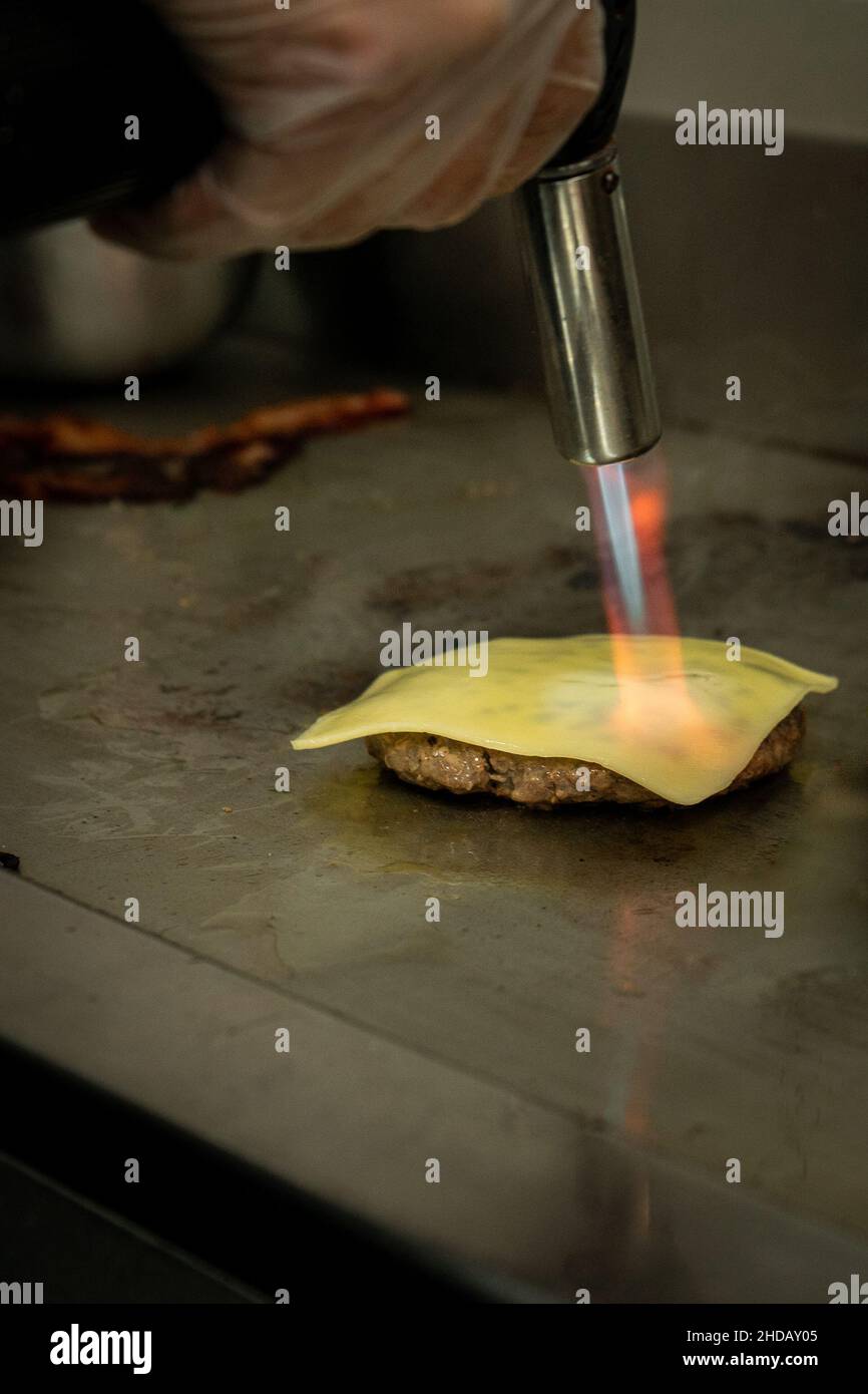 Vertical shot of a chef melting cheese with a flame torch Stock Photo ...