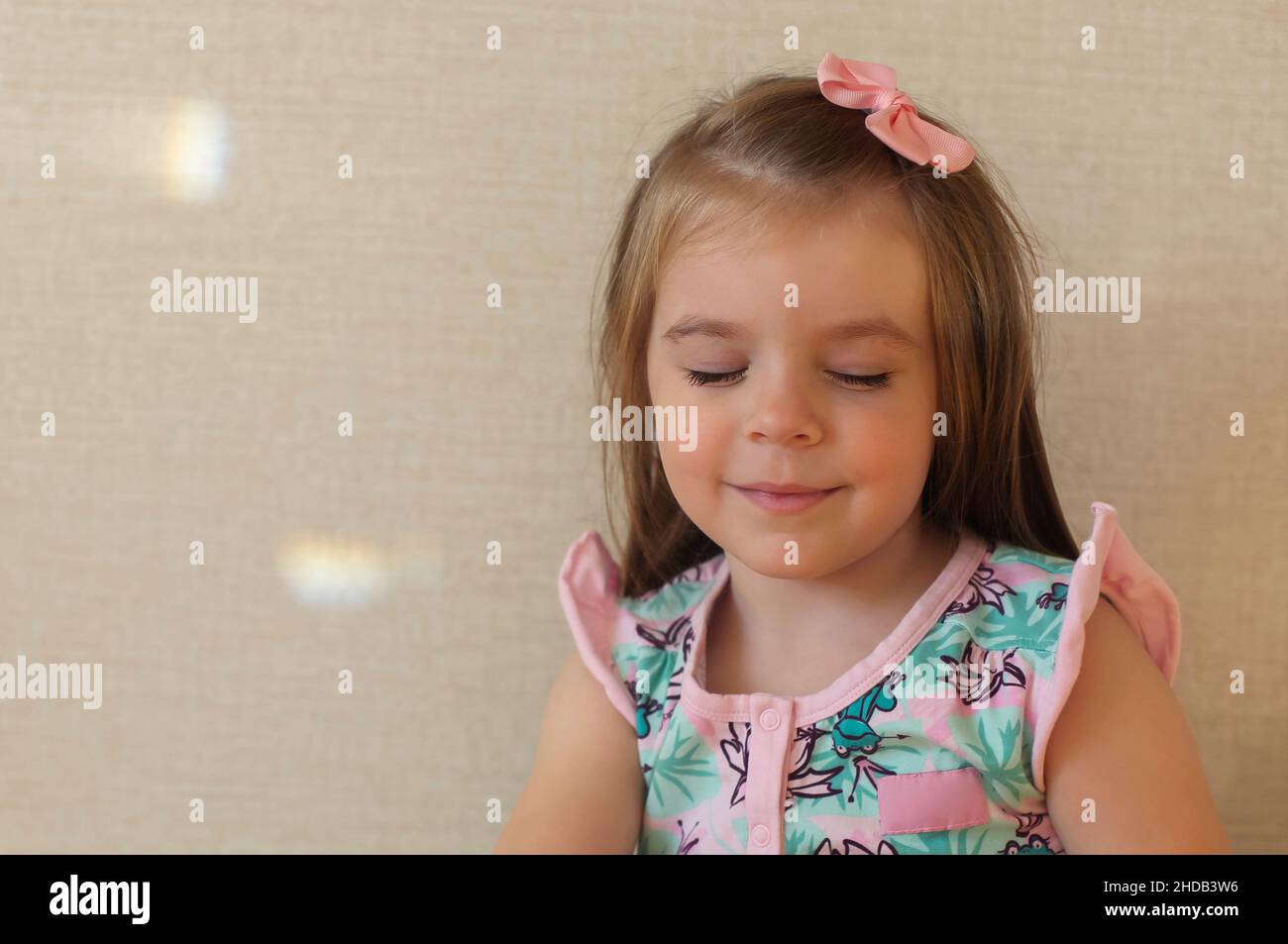 Close up of cute adorable smiling little girl with closed eyes against ...