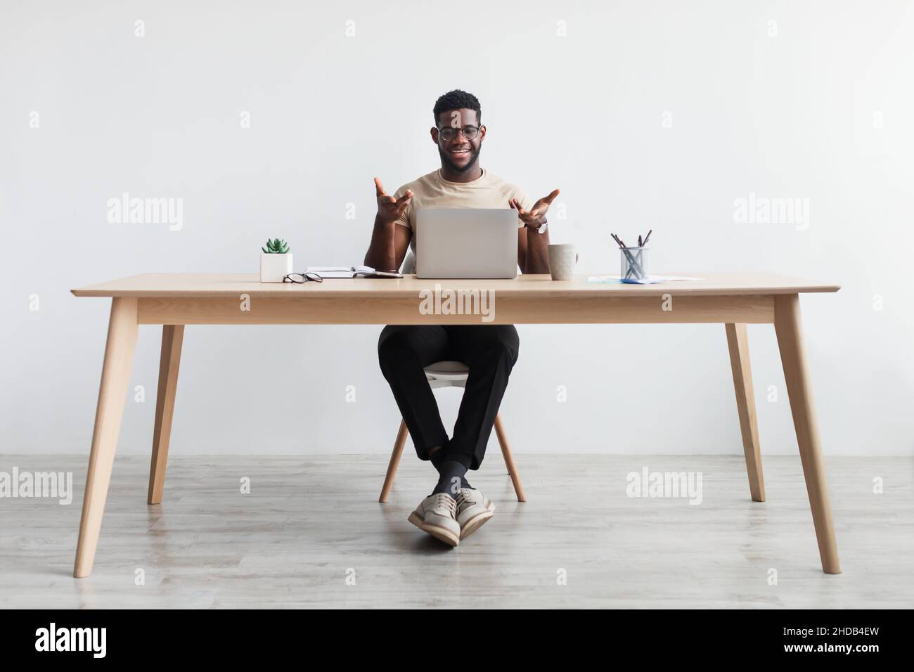 Handsome millennial black man working on laptop, making video call ...