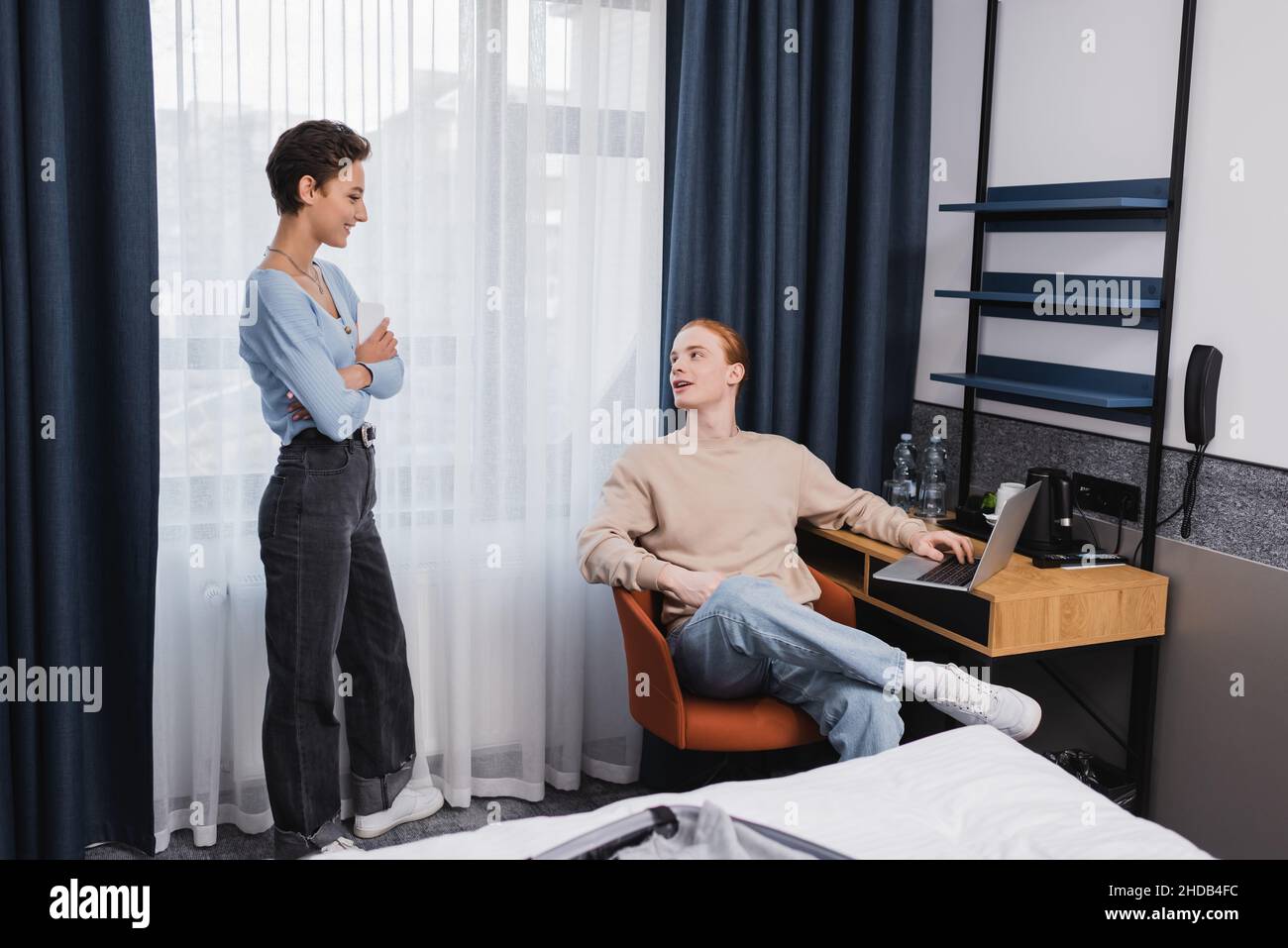 Positive couple using devices in modern hotel room Stock Photo - Alamy