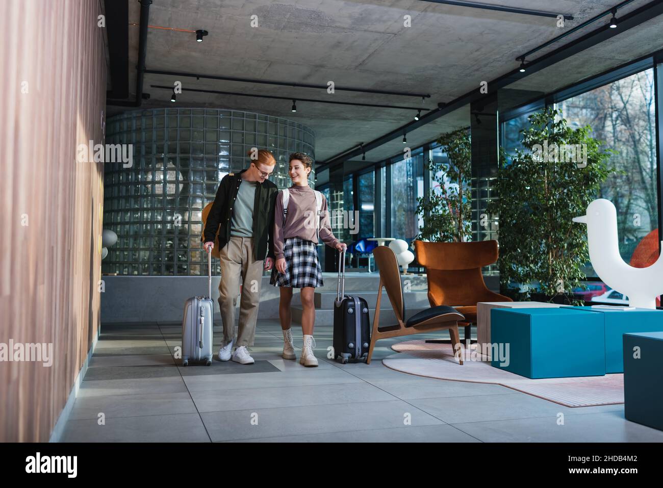 Smiling couple with suitcases talking in hotel lobby Stock Photo - Alamy