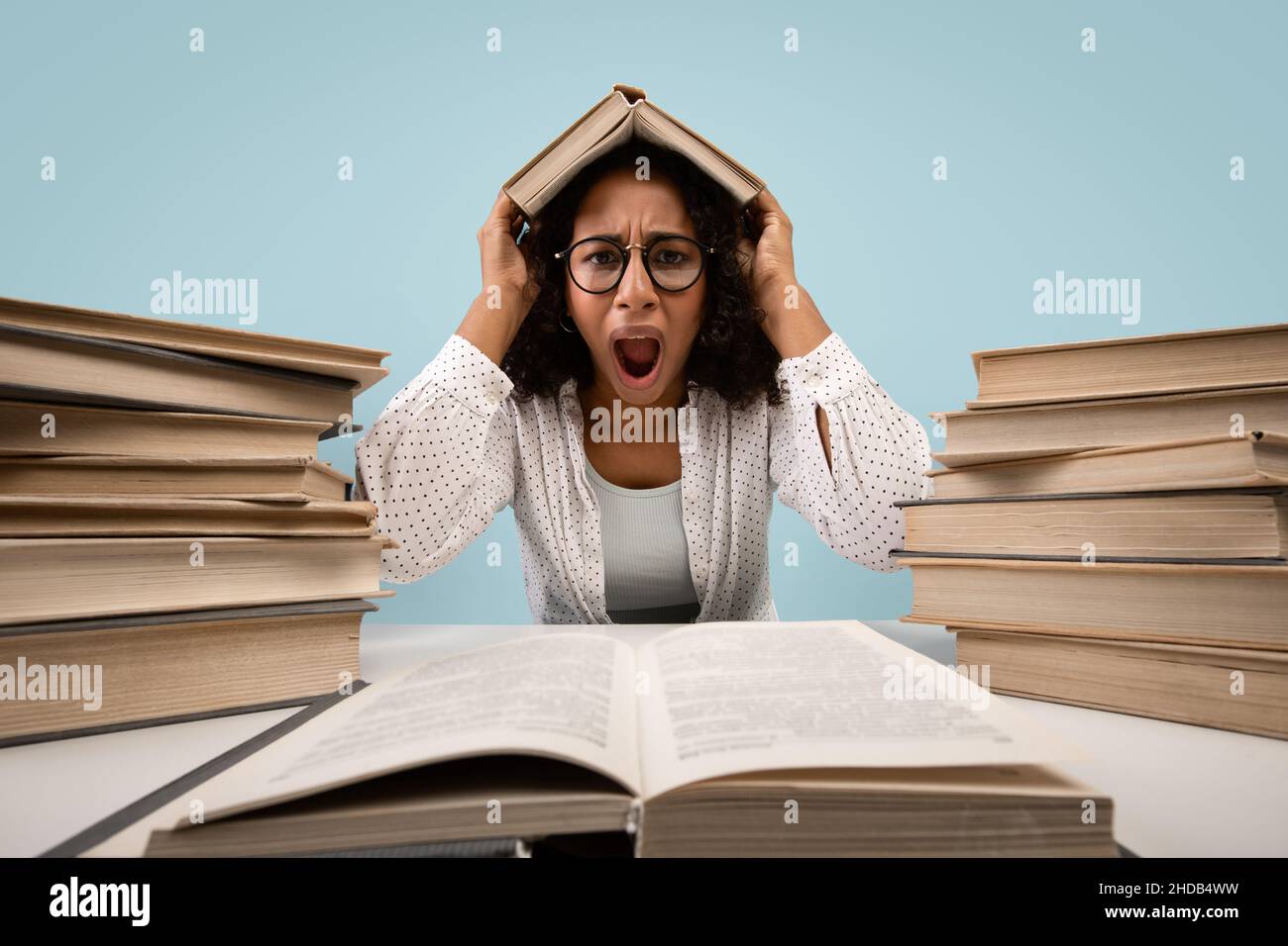 Furious young black woman putting book on her head and screaming on ...
