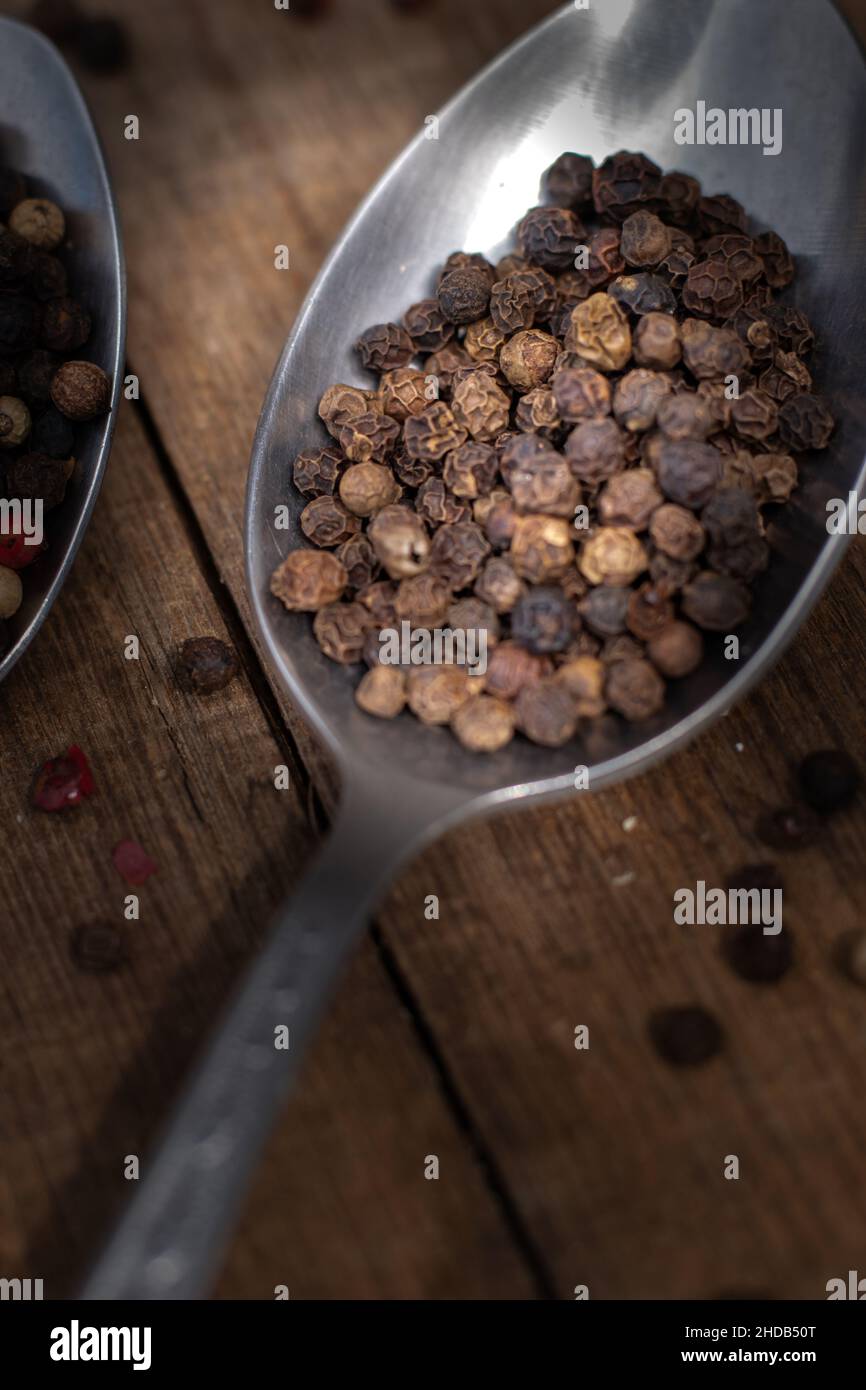 Close-up macro shot of various colored peppercorns layed on a sppon ...