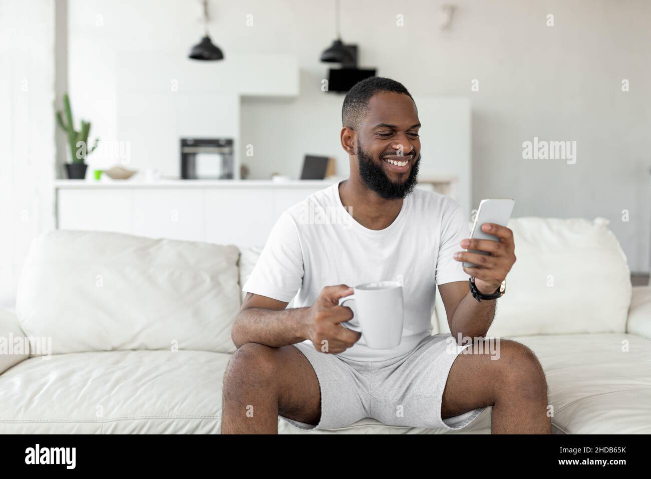 Black man using his smartphone drinking coffee Stock Photo - Alamy