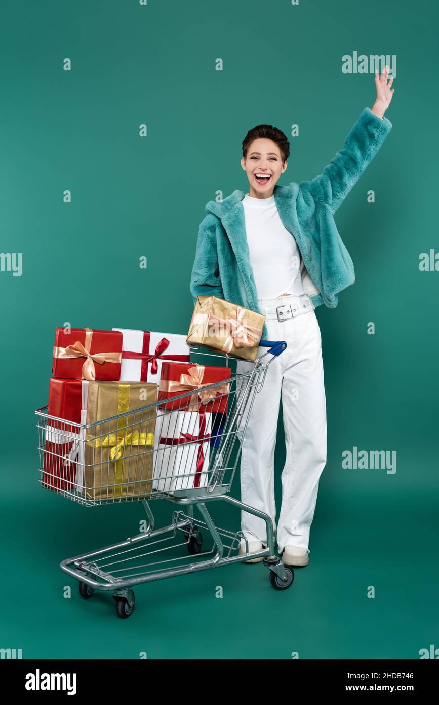 full length view of excited woman in trendy clothes waving hand near ...