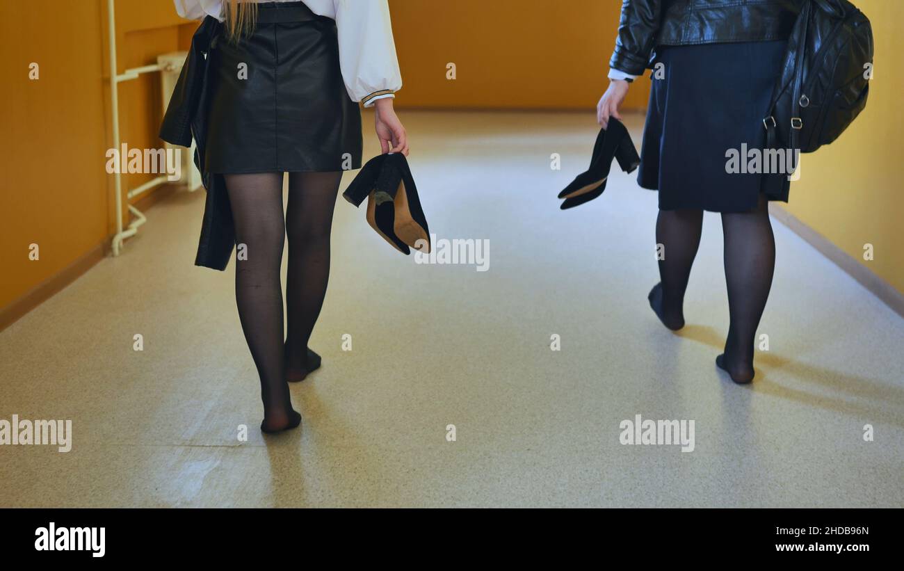 Barefoot girls students are tired at school with shoes in their hands ...