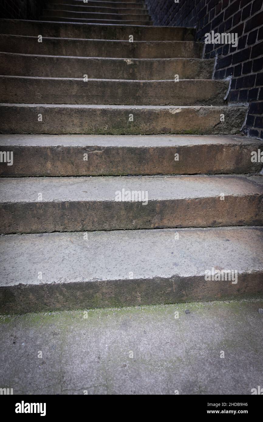 Old narrow, weathered slightly damaged stony staircase at day. Nobody ...