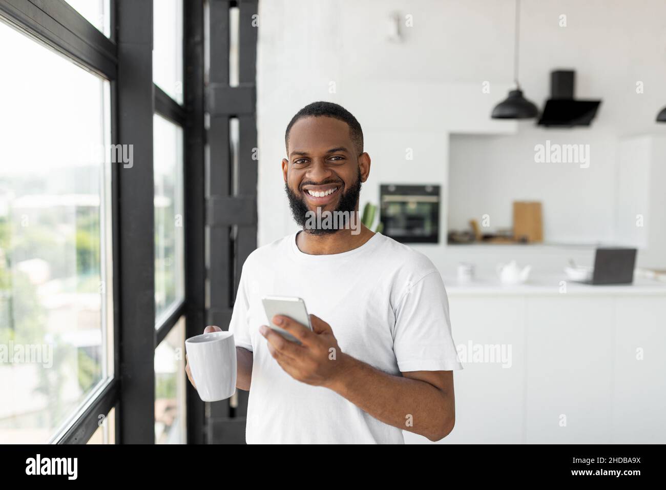 Black man using his smartphone drinking coffee Stock Photo - Alamy