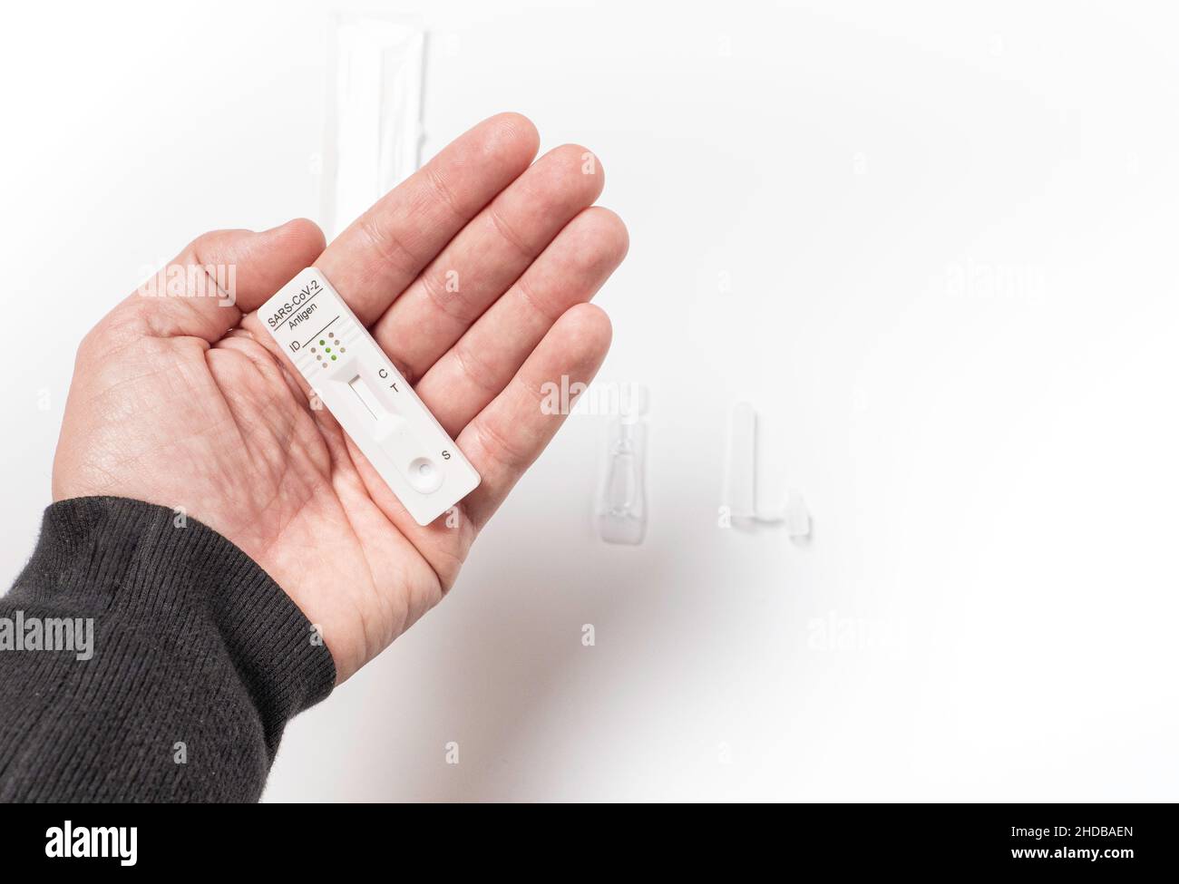 Caucasian man's hand showing a rapid antigen test on a white background ...