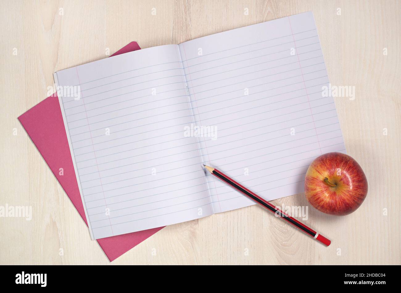 School notebook with pencil and red apple on the light work table. Top ...