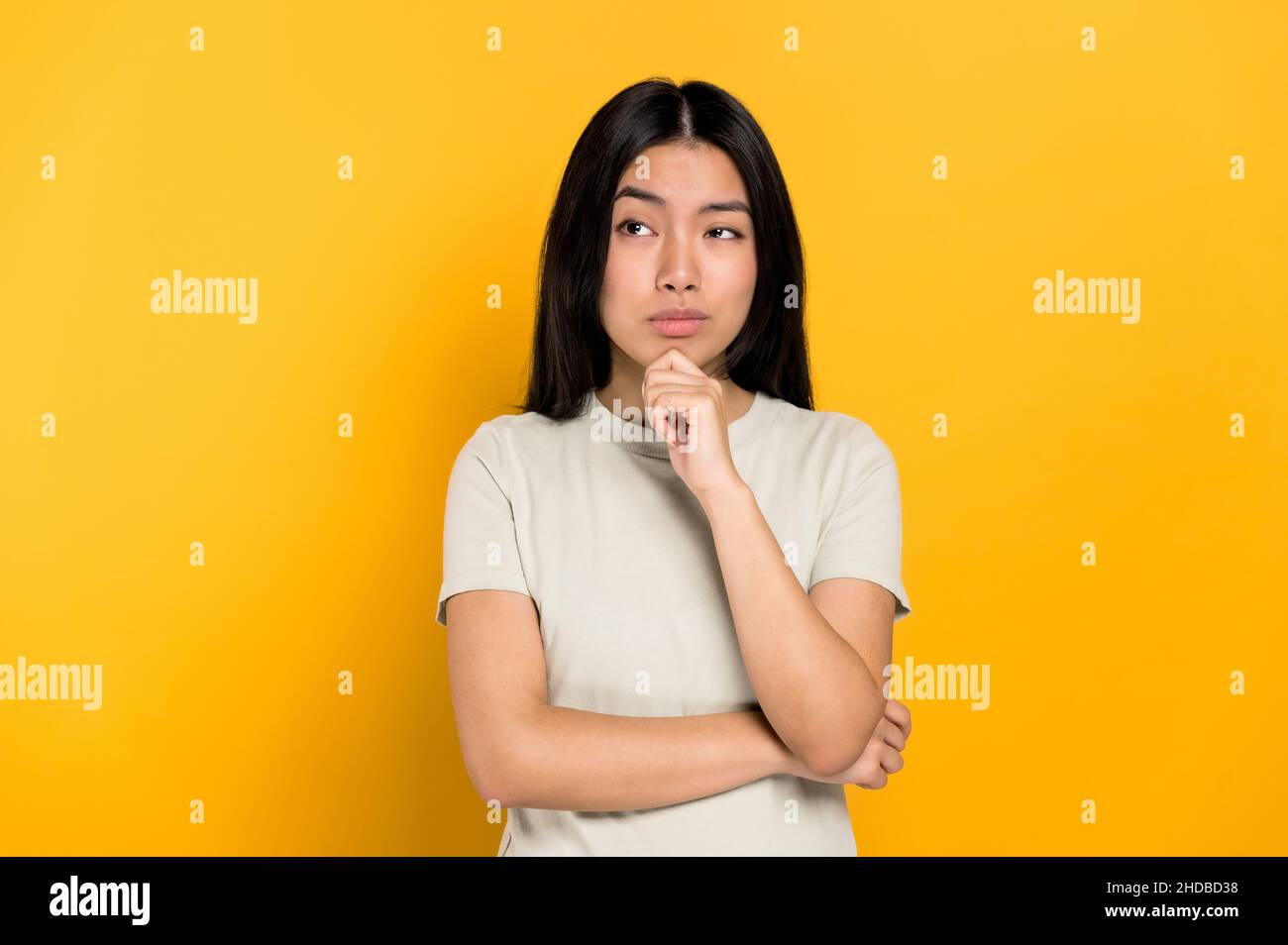 Pensive millennial smart Asian brunette young woman, minded, thinking ...