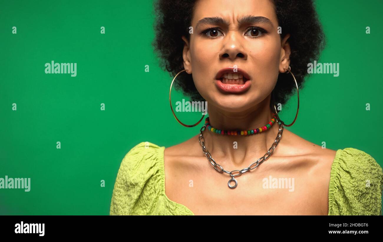 Angry African American Woman In Hoop Earrings Isolated On Green Stock