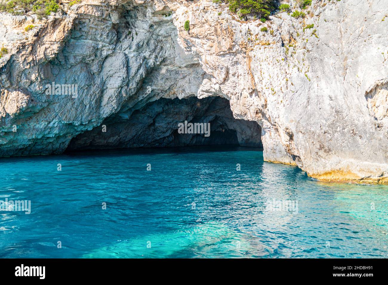Layered light-colored rocks creating dark cave in sea beach of Corfu ...