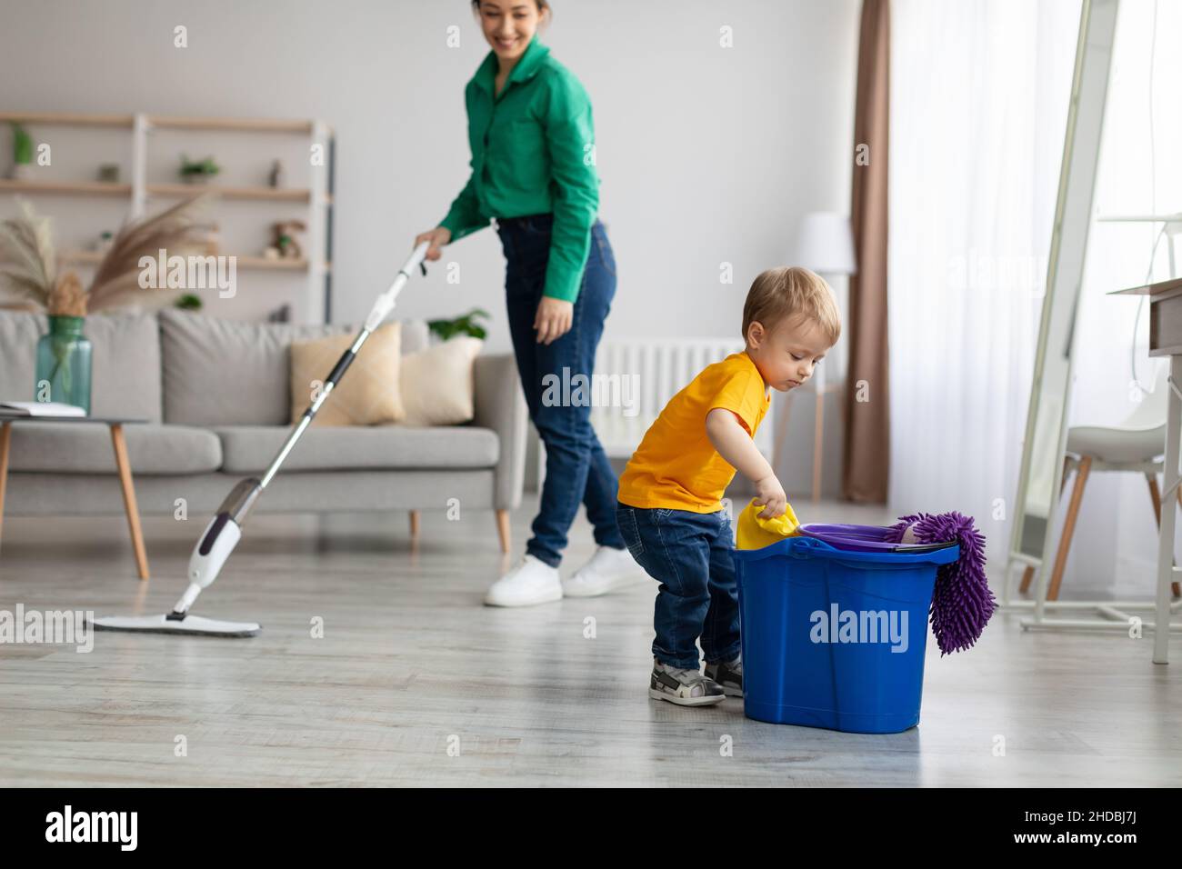Little helper. Adorable toddler boy helping mom cleaning at home, kid ...