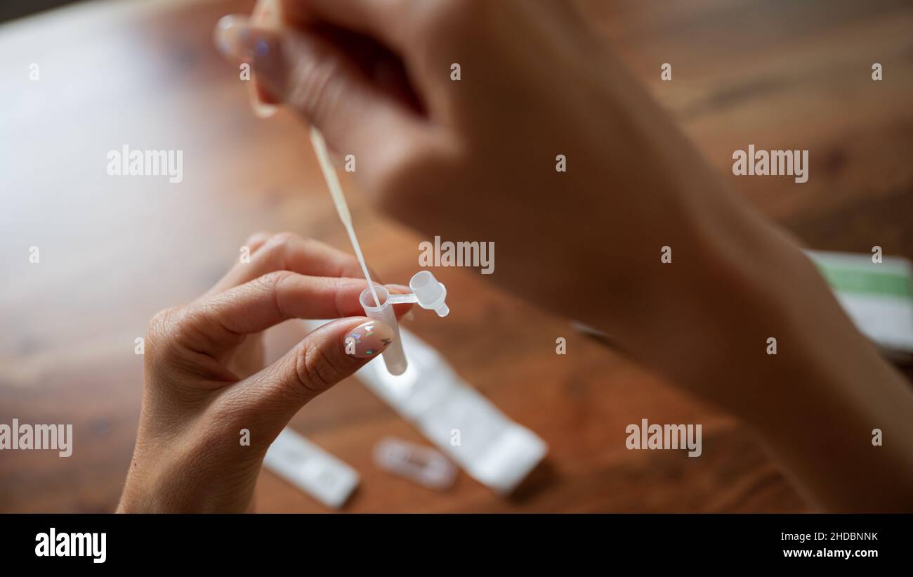 Closeup view of female hand placing coronavirus sample stick swab in a ...
