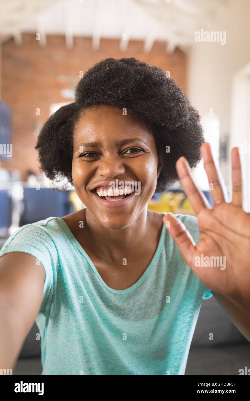 Portrait of happy african american woman waving hand on video call at ...