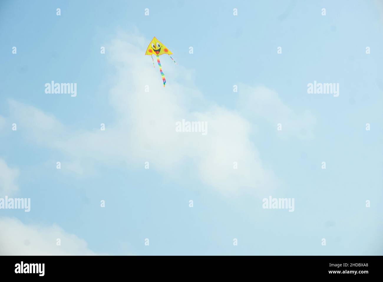 Yellow kite with a smile flying in the sky Stock Photo - Alamy