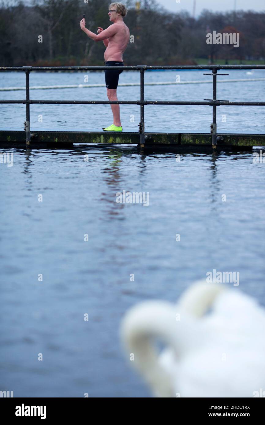 A swan is seen as swimmers taste a morning dip in the Serpentine, Hyde ...