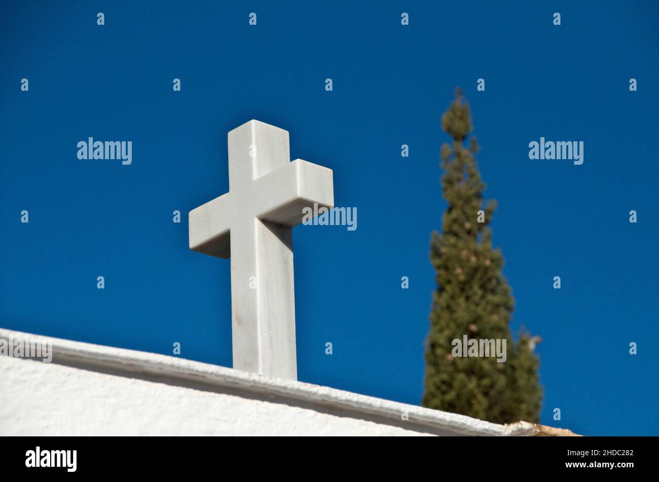 White marble cross in front of cypress tree in cemetery, Andalusia ...