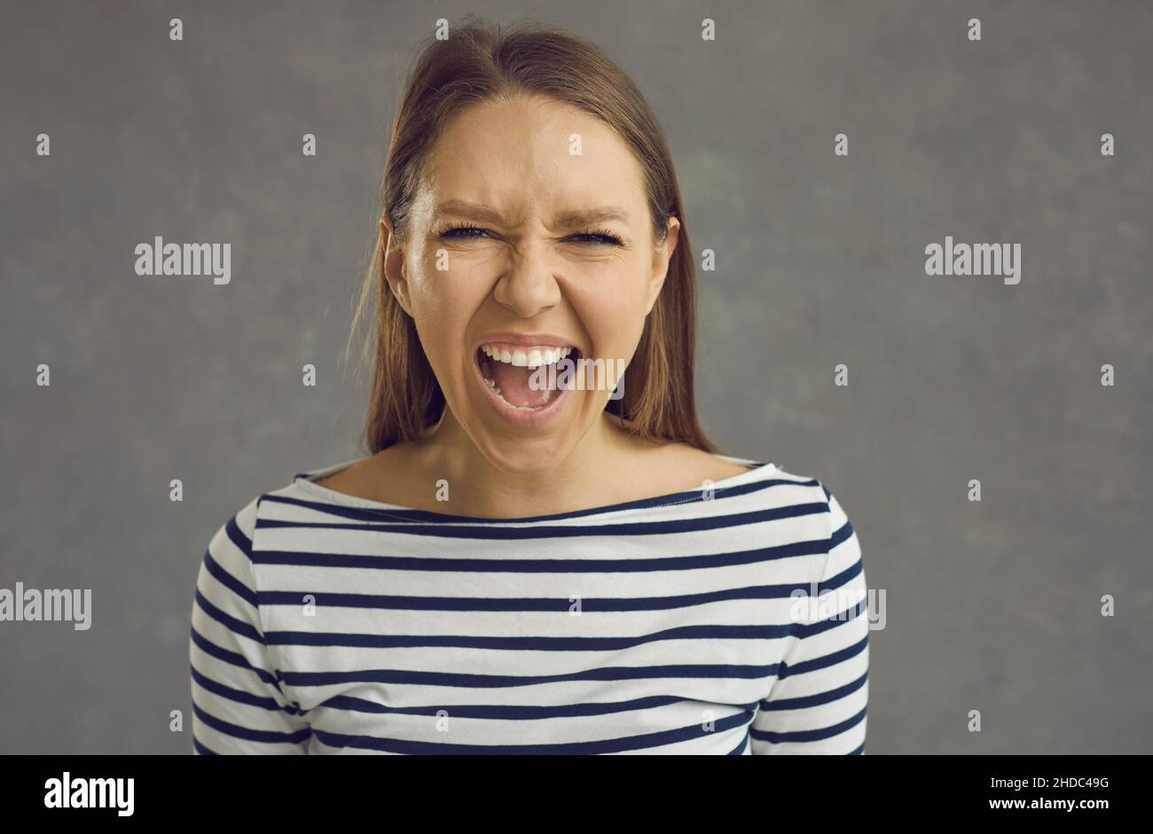 Studio portrait of an angry stressed crazy young woman screaming loudly ...