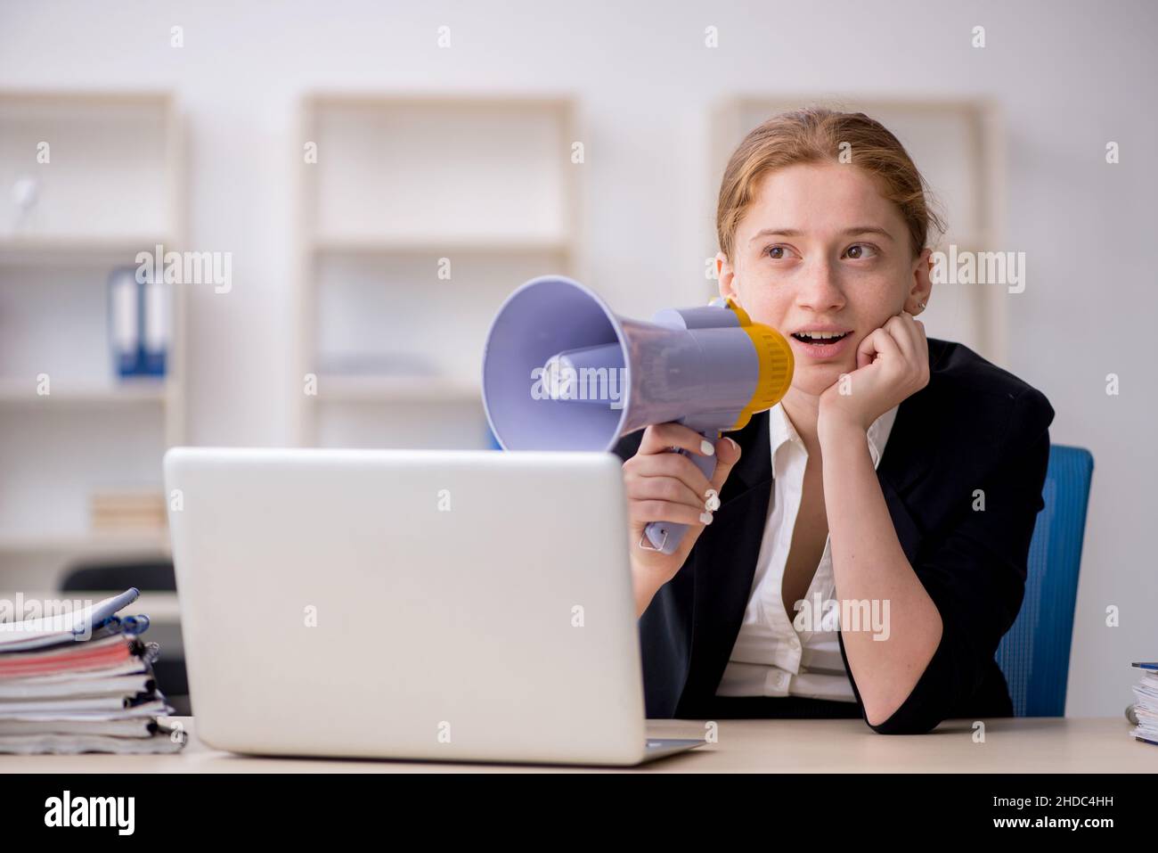 Female employee holding megaphone at workplace Stock Photo - Alamy