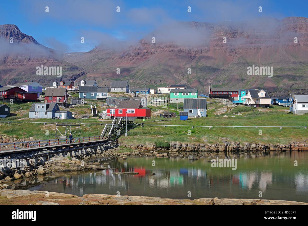 Simple bridge leading to houses reflected in a body of water ...