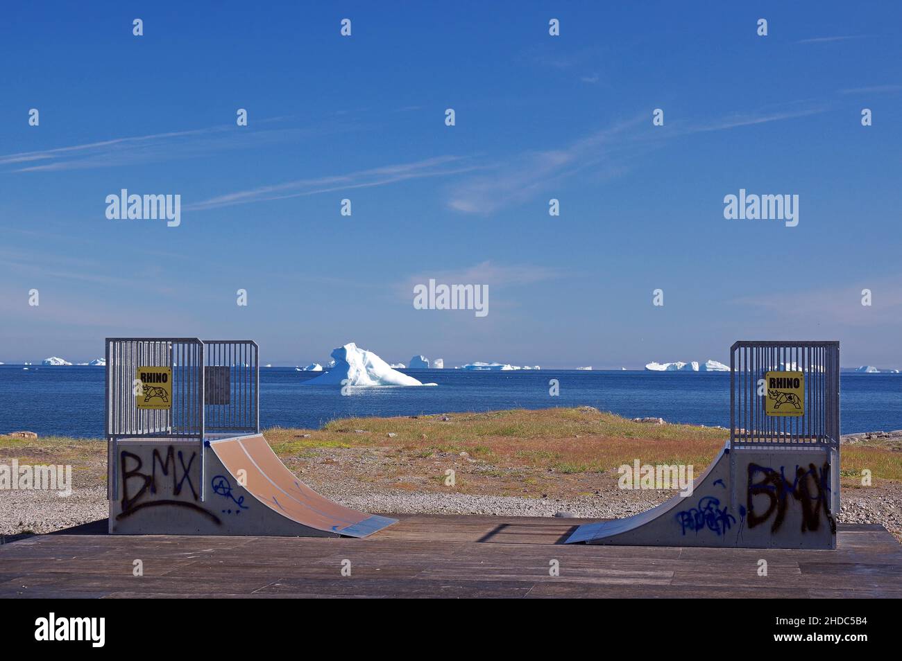 Skating rink painted with graffiti in front of icebergs floating in a ...