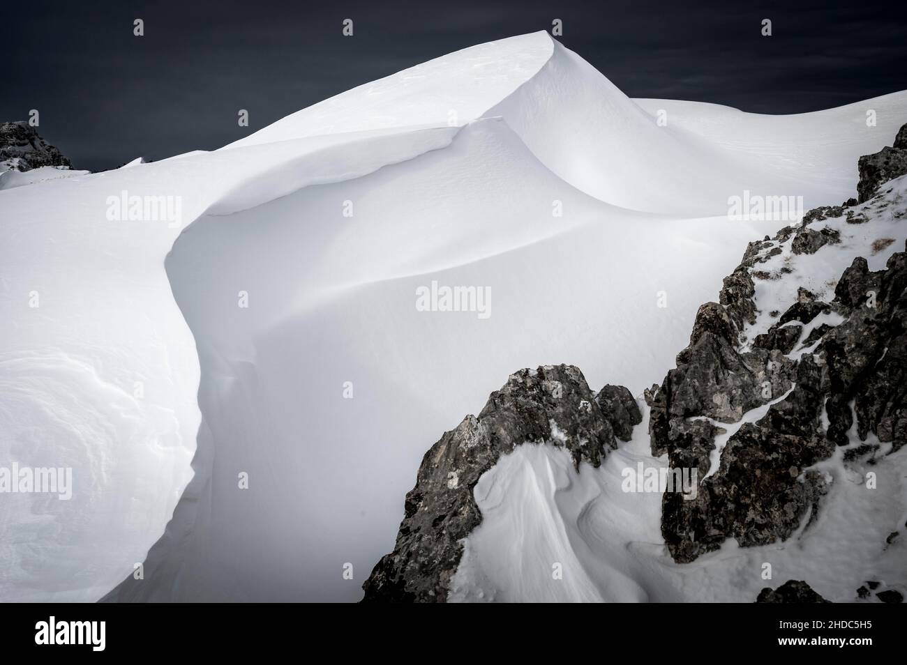 Snow cornice against a dark sky at the summit of Toreck, Riezlern ...