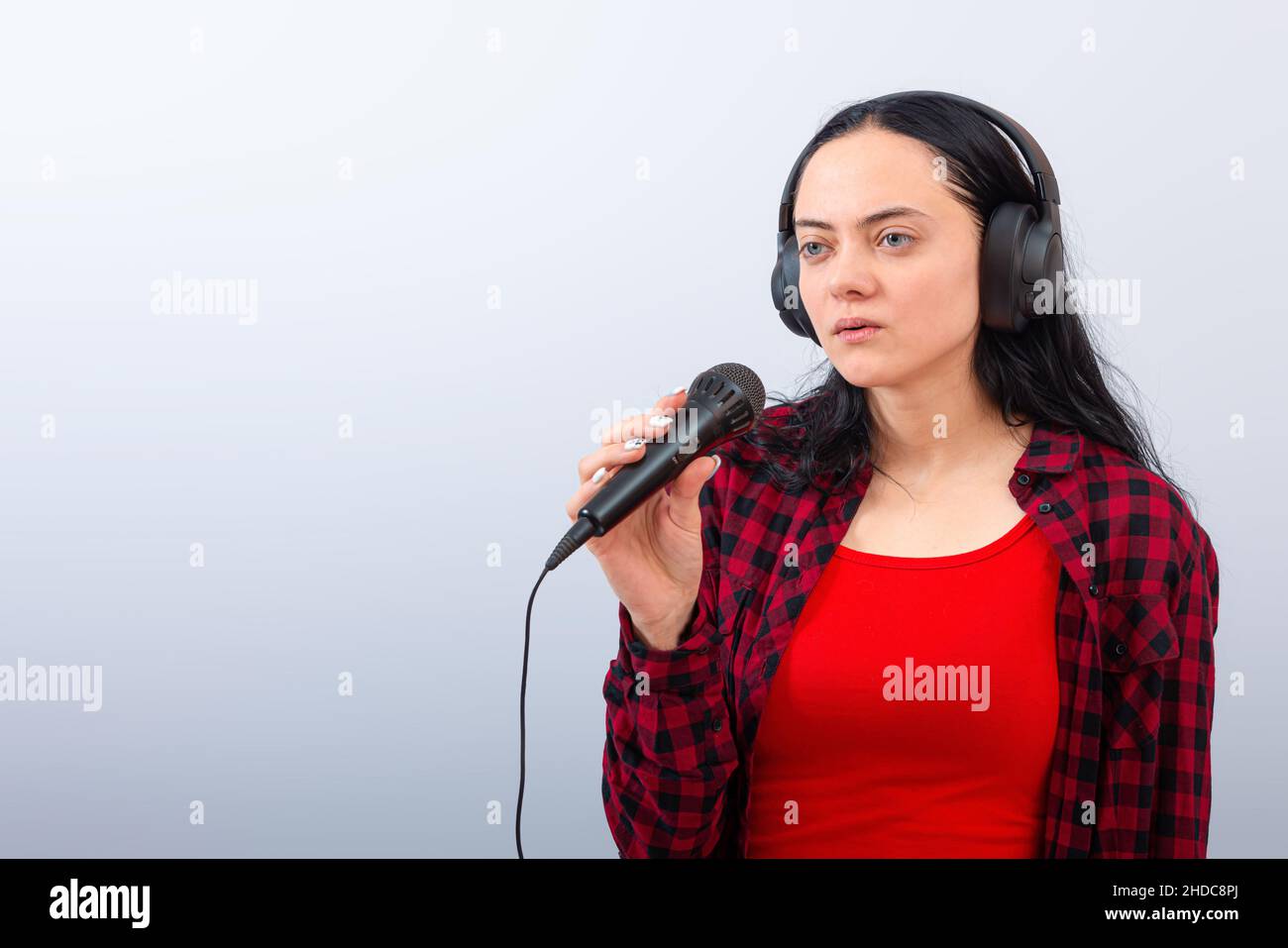 expressive female singing with a microphone and headphones, isolated on ...