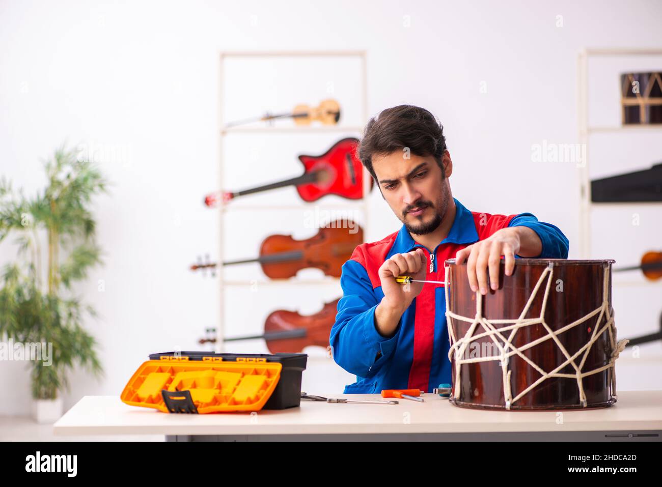 Young repairman repairing musical instruments at workplace Stock Photo ...