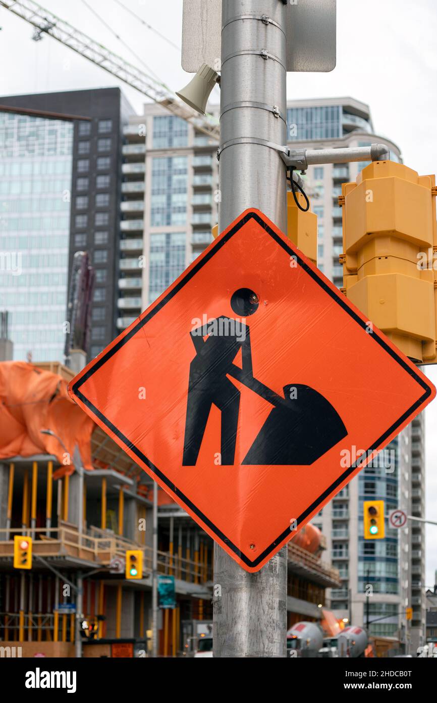 Construction orange sign near construction site against tall buildings ...