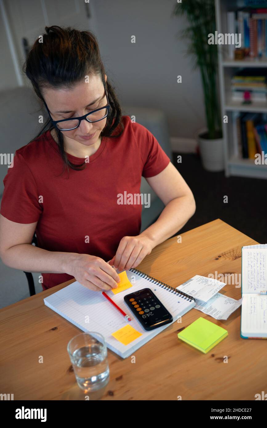 Small business owner doing paperwork in a casual home office ...