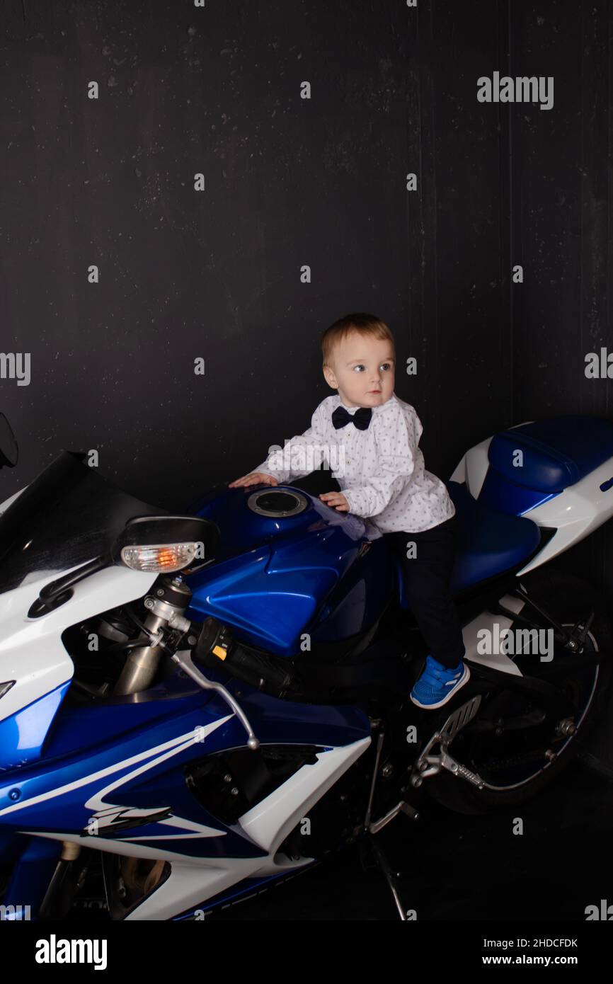 pretty charming little boy on motorcycle on black background. little ...