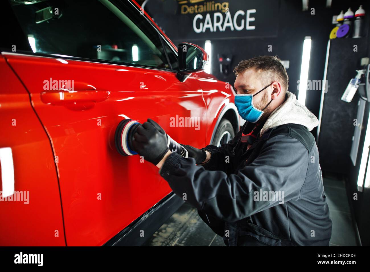 Car detailing concept. Man in face mask with orbital polisher in repair ...