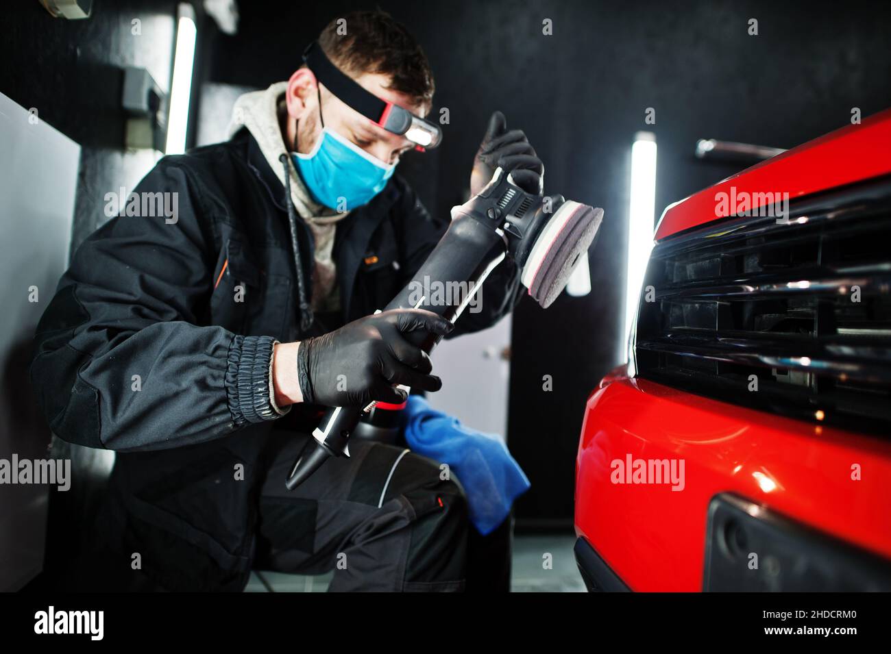 Car detailing concept. Man in face mask with orbital polisher in repair ...