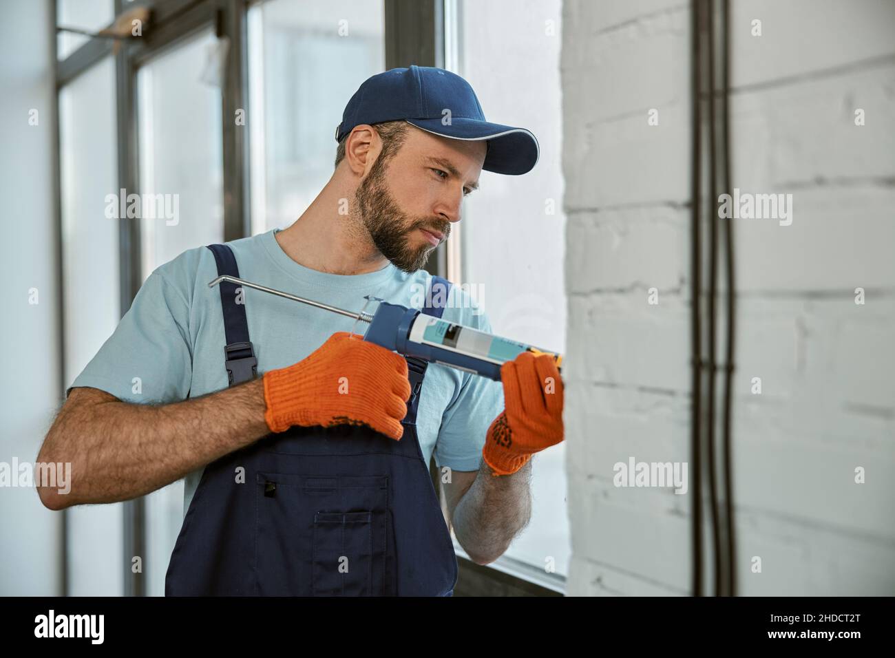 Bearded young man repairing window with special tool Stock Photo - Alamy